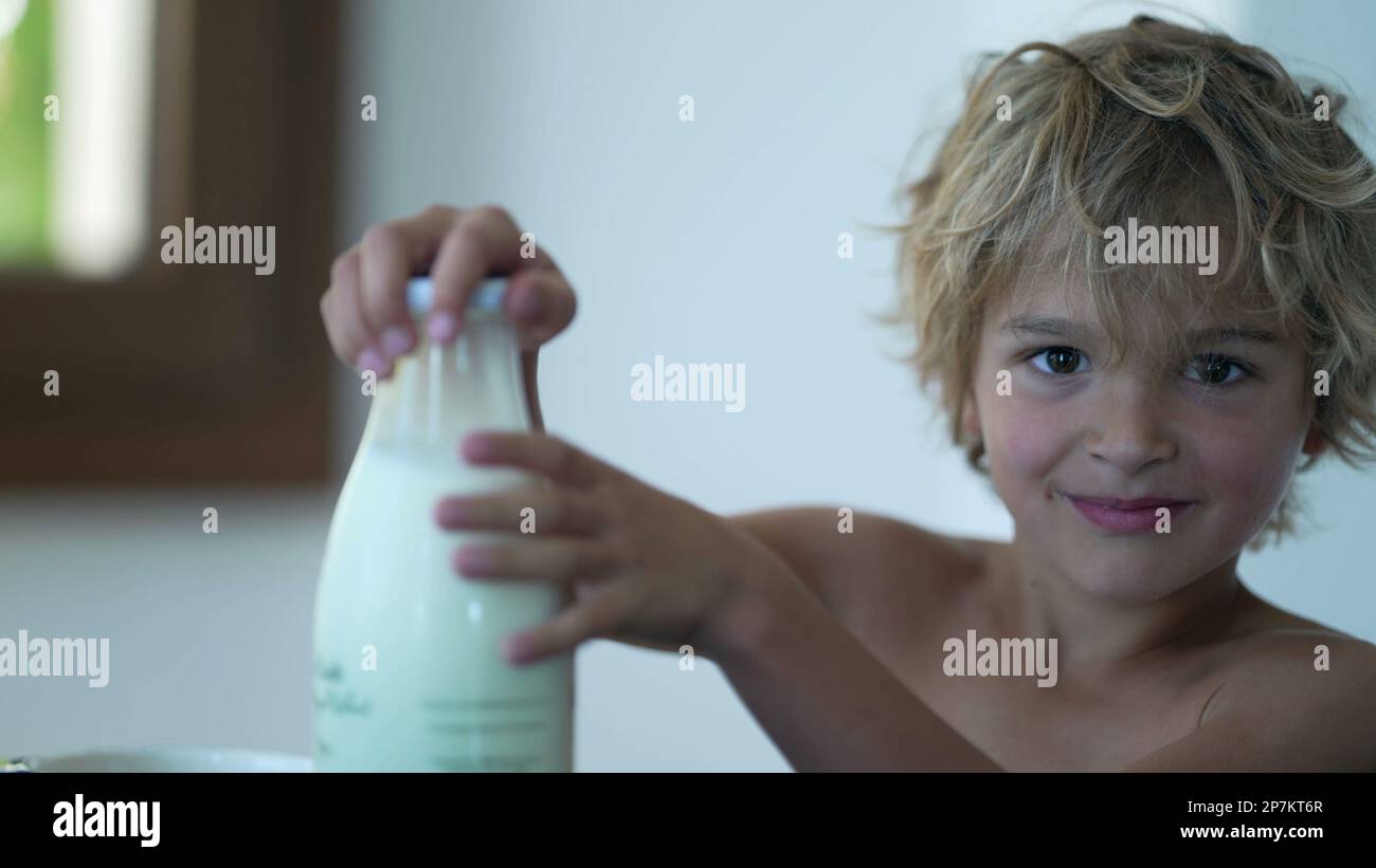 One young boy trying to open bottle of milk. Kid unable to free glass ...