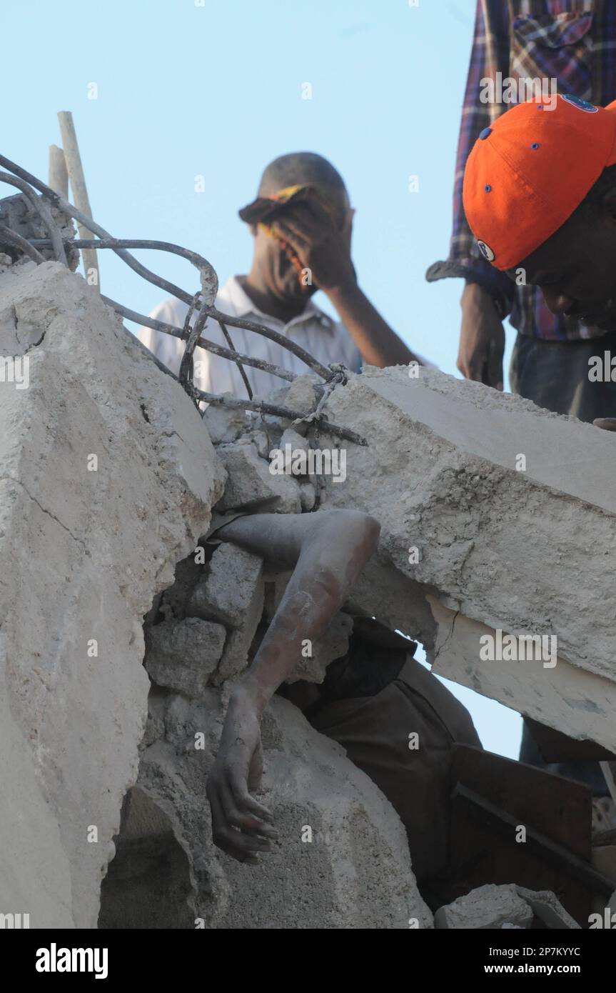 A man gestures behind a person trapped in the rubble of a collapsed ...