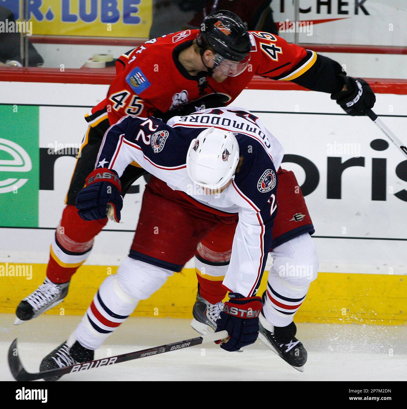 Columbus Blue Jackets' Mike Commodore, bottom, takes a hit from Calgary ...