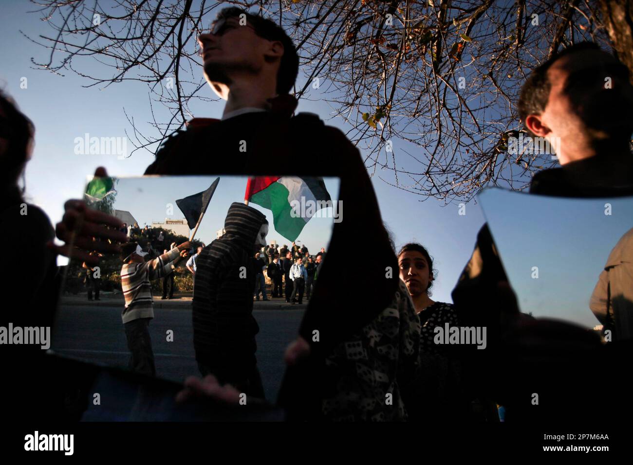 Israeli and Palestinian left-wing activists hold mirrors during a ...