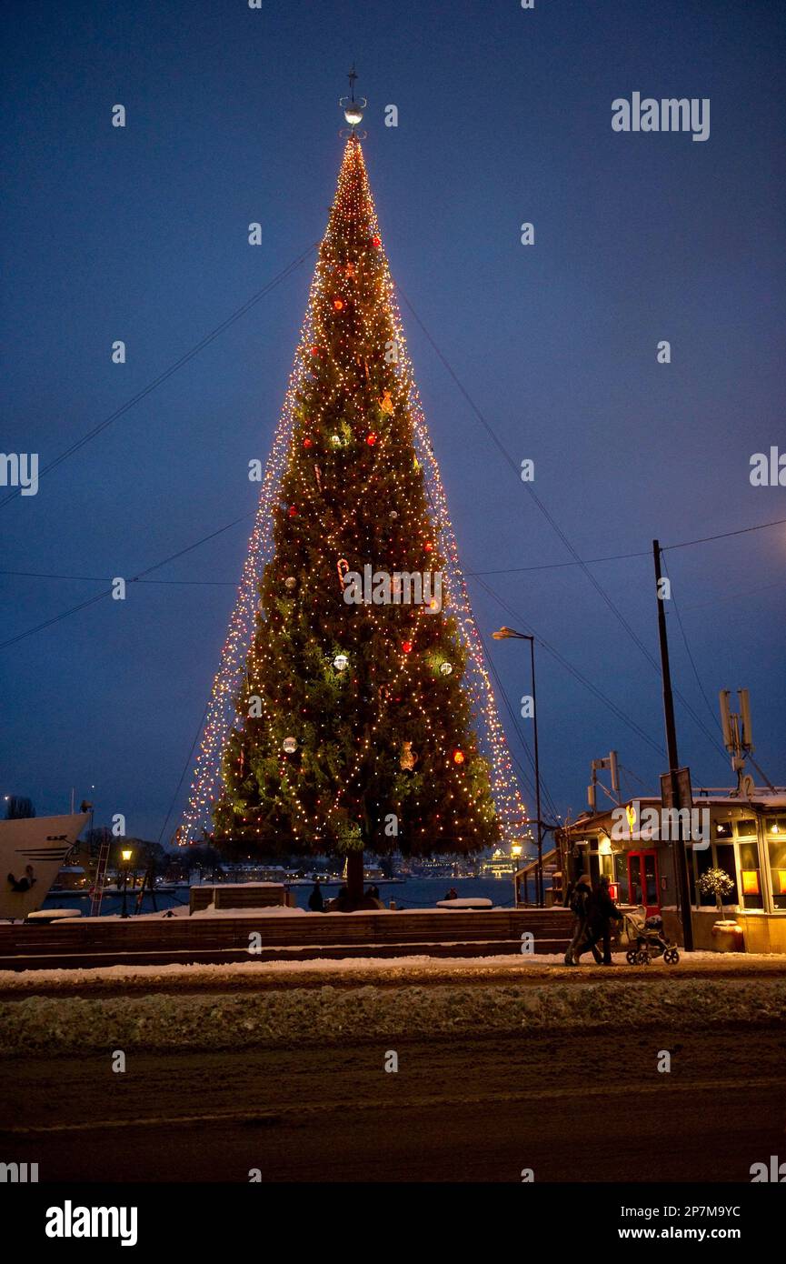 People pass a traditional Christmas tree on Skeppsbro quay in the old ...