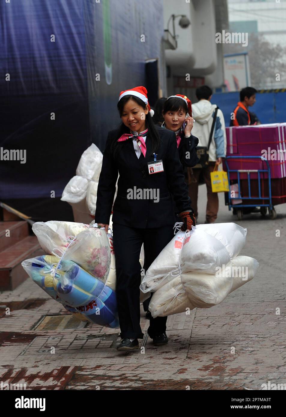 Shopping mall workers wearing Christmas hats deliver products in ...