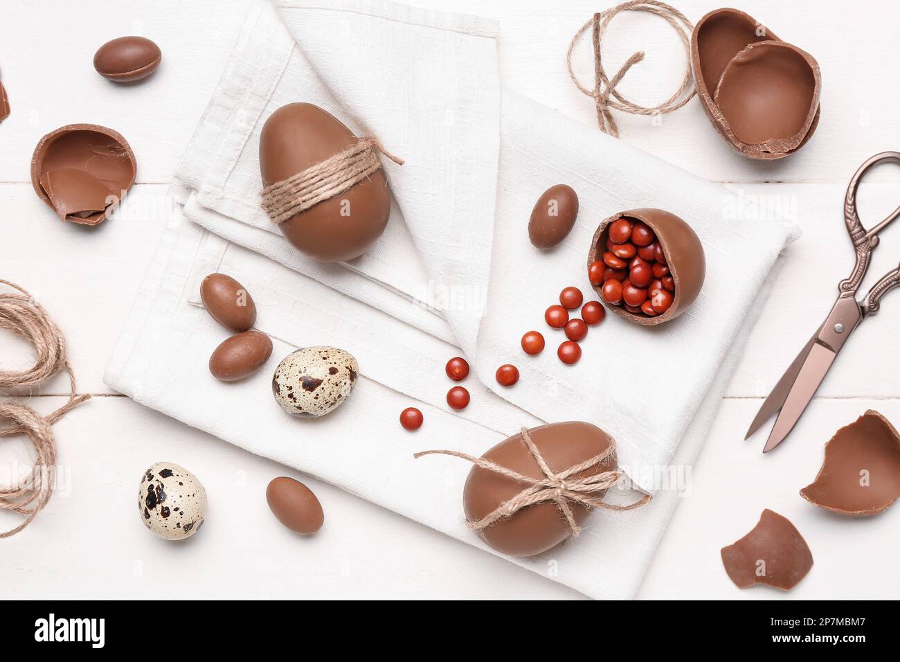 Composition with candies and chocolate Easter eggs tied with thread on ...