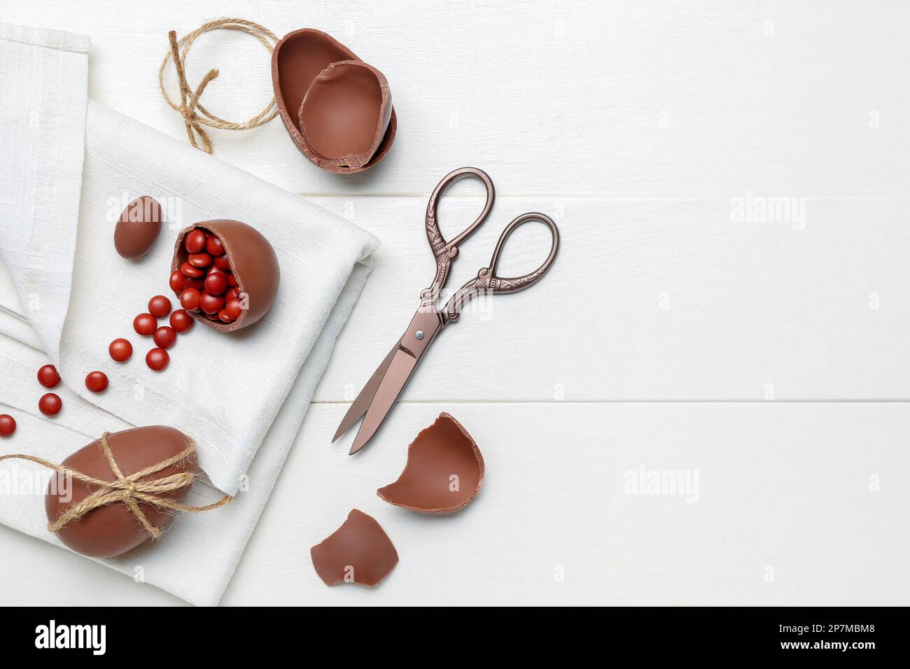 Composition with chocolate Easter eggs, candies, thread and scissors on ...