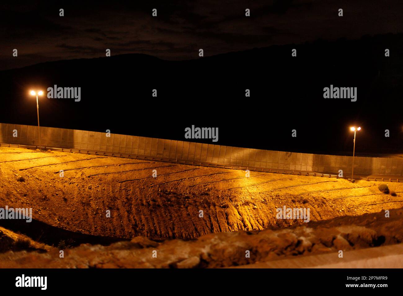 In this Dec. 8, 2009 photo, flood lights illuminate the border wall ...