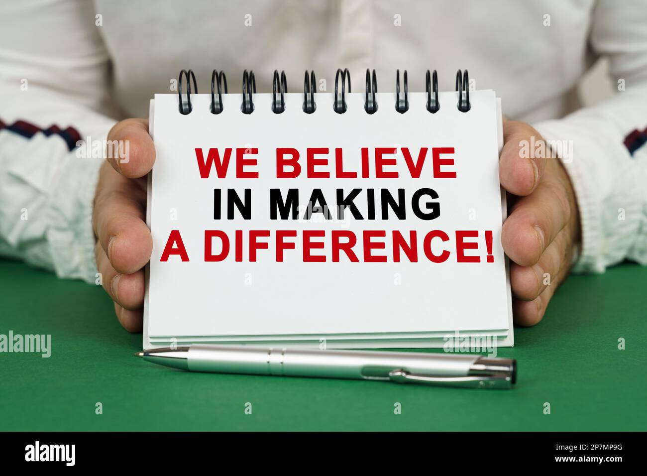 A man holds a notepad in his hands with the inscription - We Believe in Making a Difference ...
