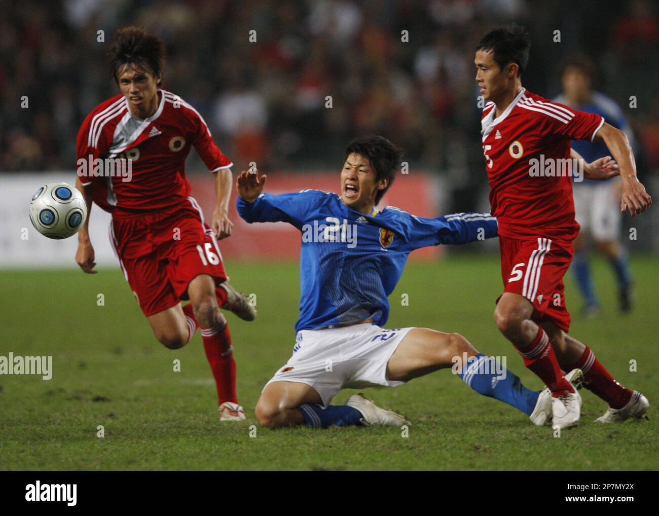 Yuya Osako of Japan, center, fights for the ball with Leung Chun Pong ...