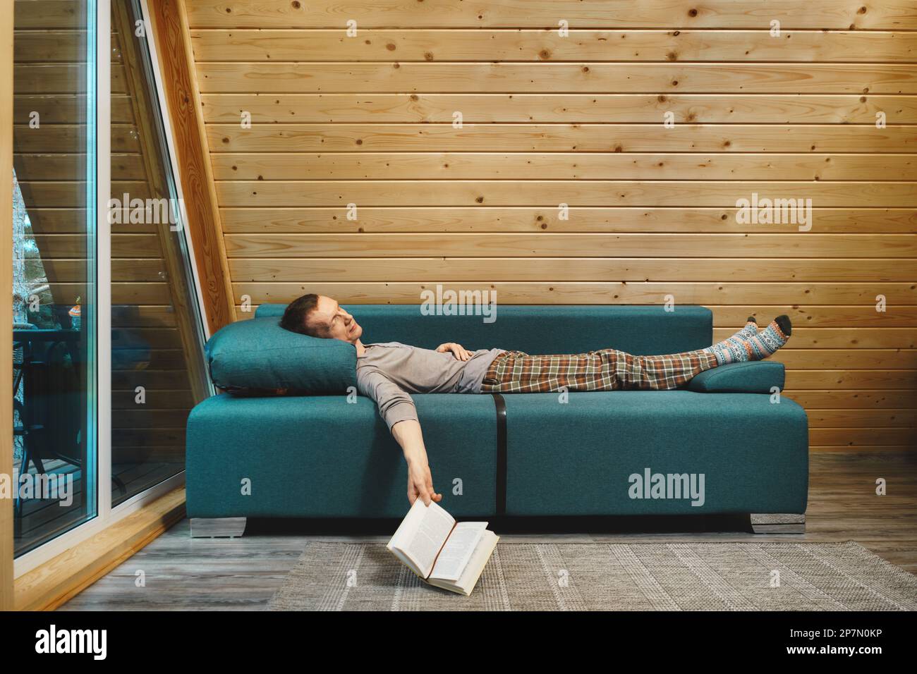 Man was reading a book in his wooden cabin in rainy day and fell asleep ...