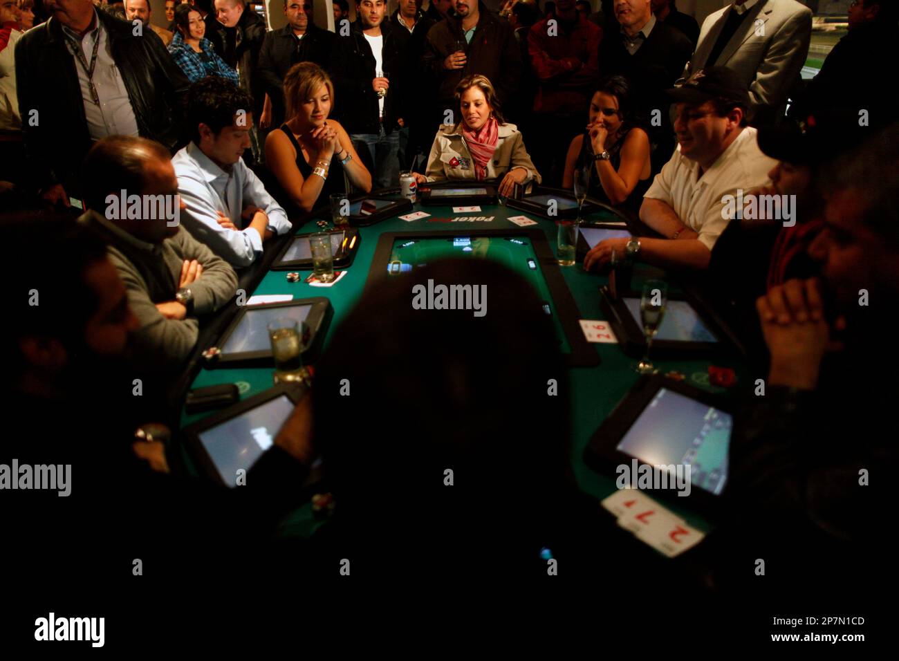 Invited guests play poker during the opening of a new poker table room ...