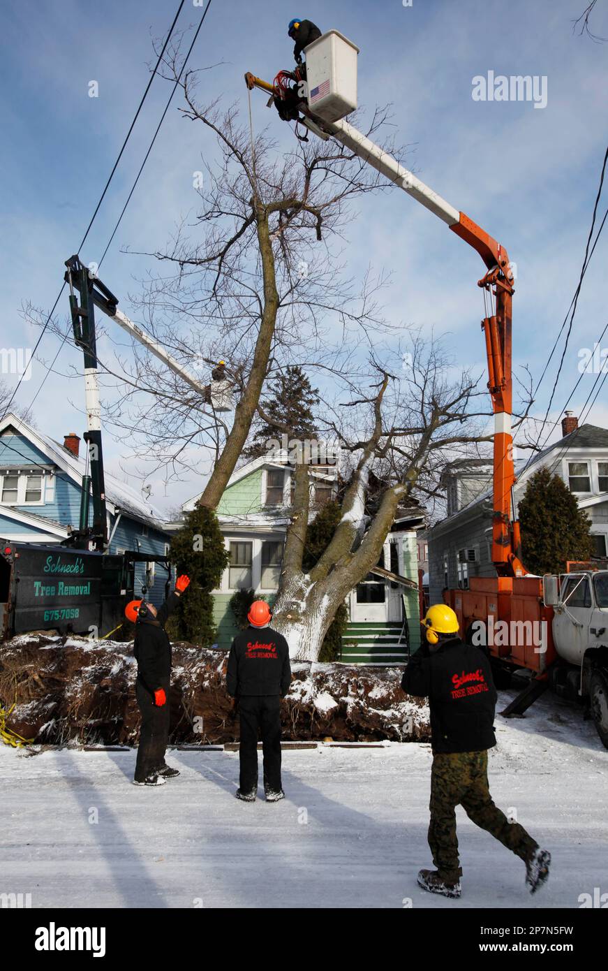 Workers remove a tree that fell on a house during a winter storm in ...