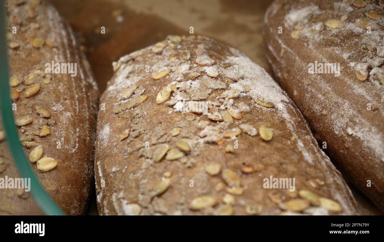 Loaves of rye farm bread lie on the wooden bakery shelf. Close-up shot ...