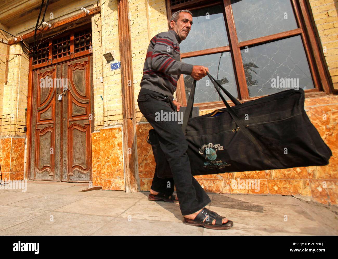 An Iraqi singer and musician carries his keyboard outside al-Madheef ...