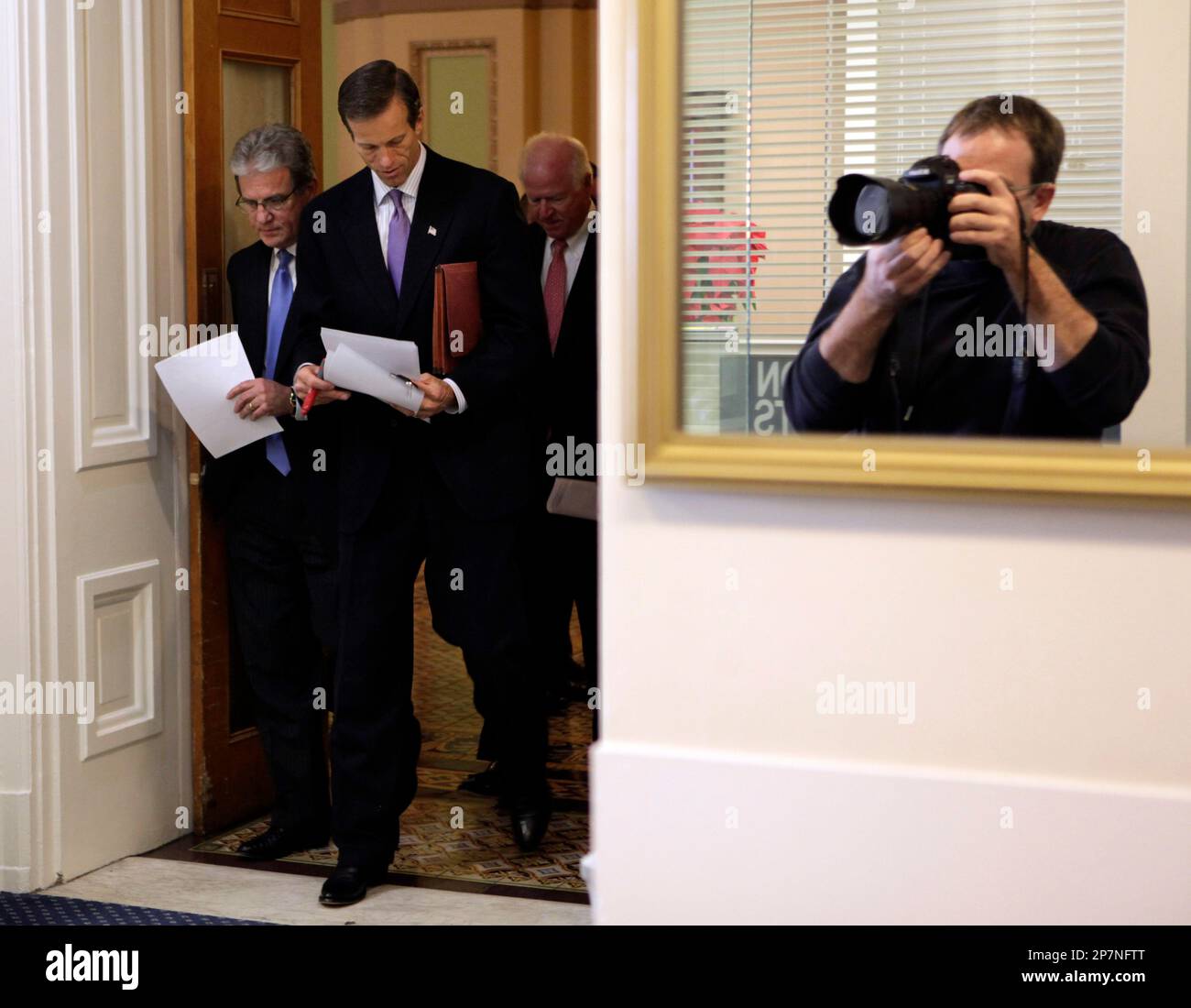 A photographer is seen in a mirror at right ,as, from left, Sen. Tom ...