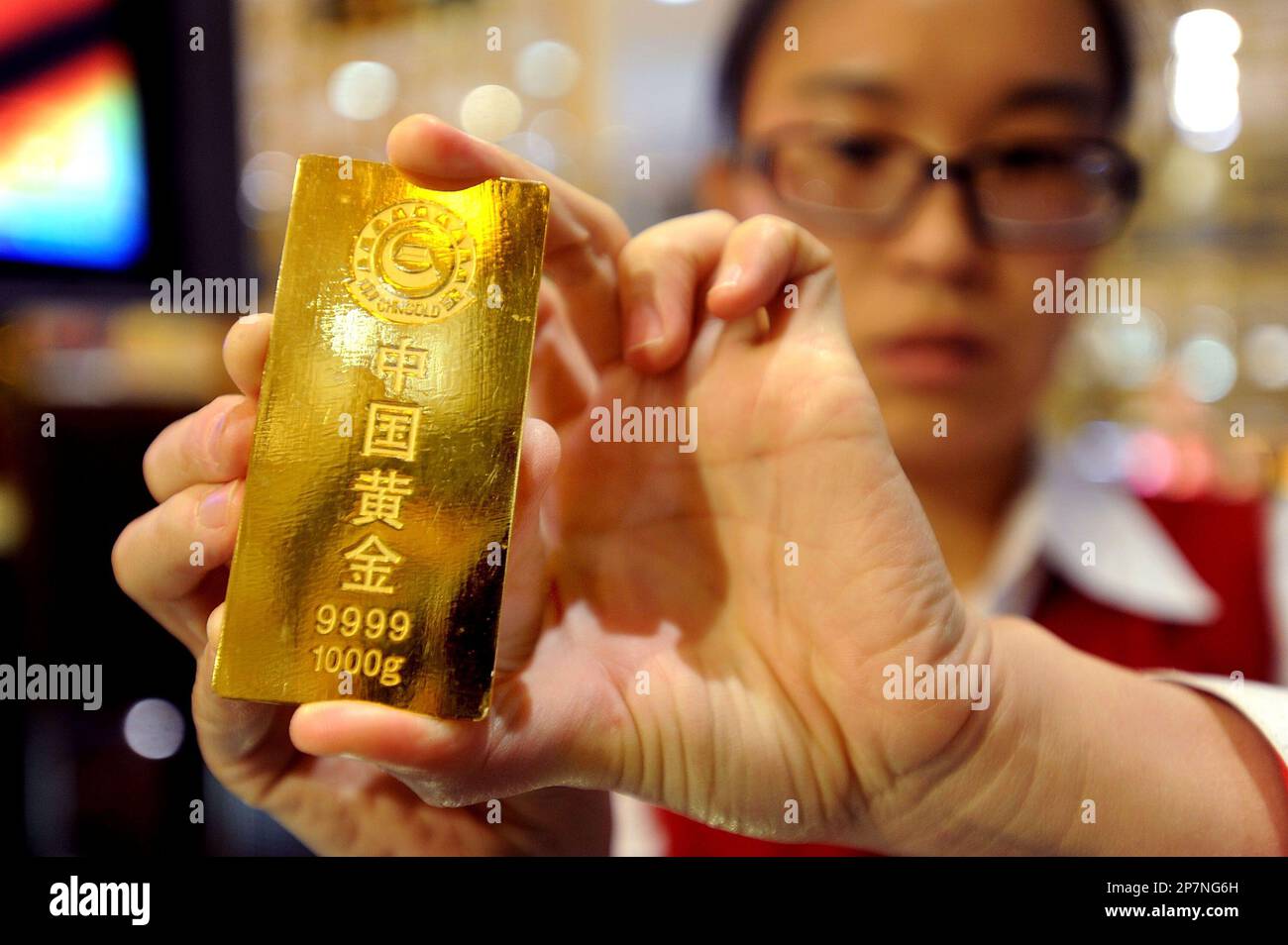 A saleswoman displays a gold bar at a shop in Shenyang in northeast ...