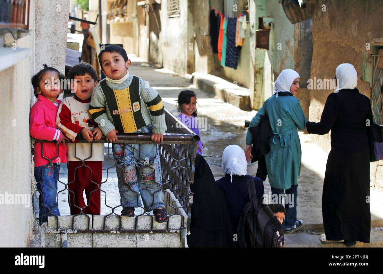 Palestinian children, left, are seen on a balcony, while a group of ...