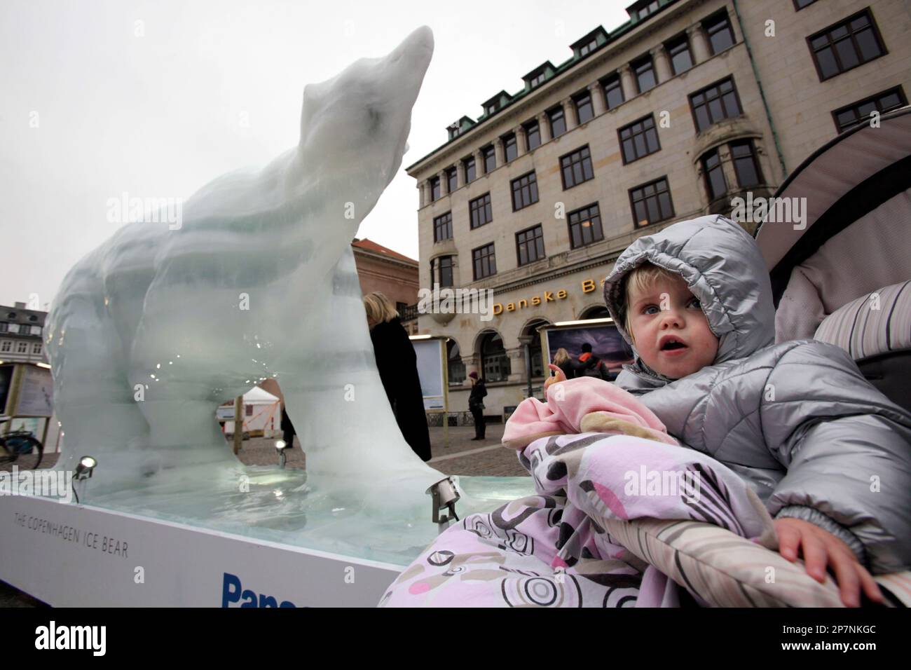 A child is seen next to a melting ice statue of a polar bear in the ...