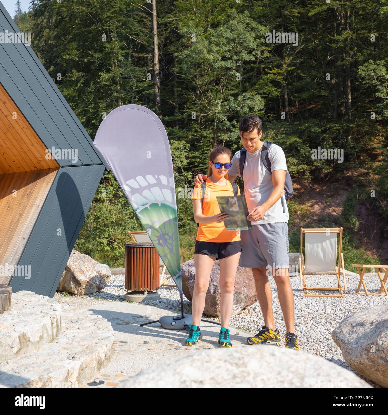 Young hiking couple reading map at tourist point outdoors Stock Photo ...