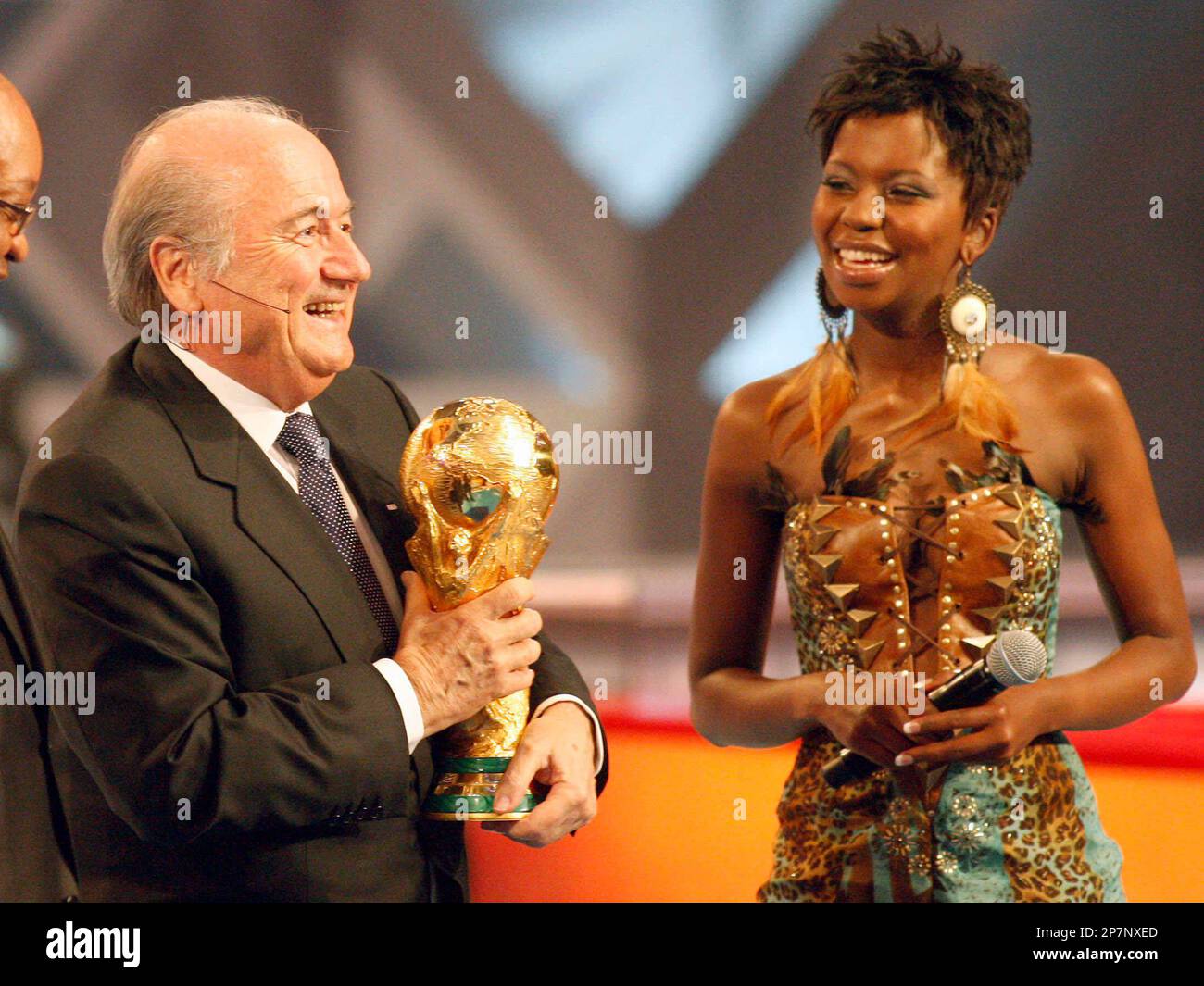 FIFA President Sepp Blatter holds aloft the trophy watched by show host ...