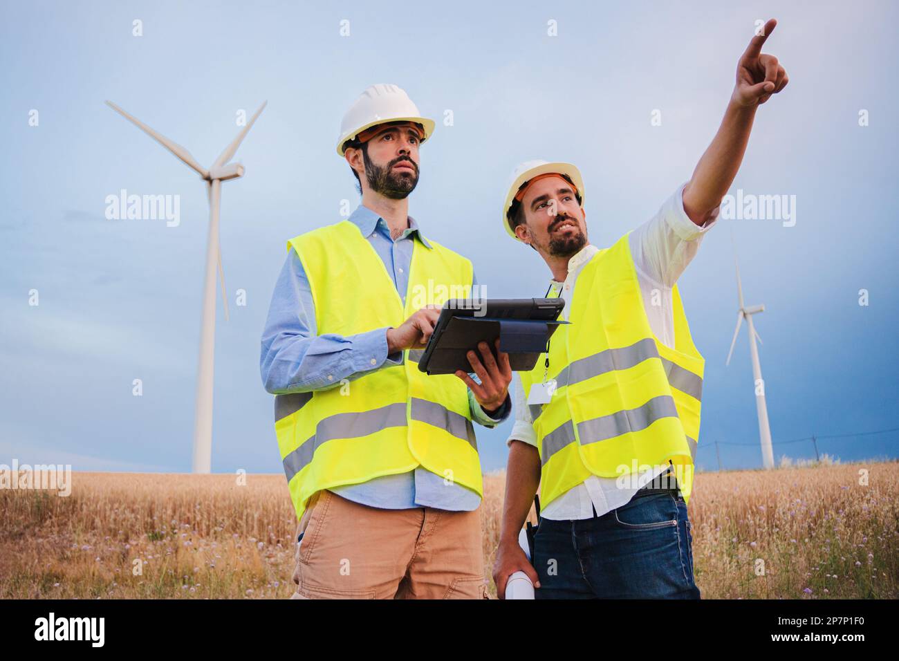 Two windmill turbine engineers working together, one technician using a ...