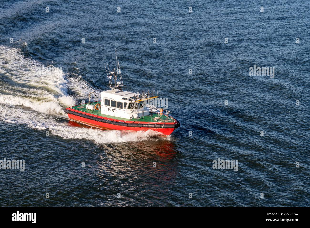 Red pilot boat speeding back to shore after escorting ship from harbor ...