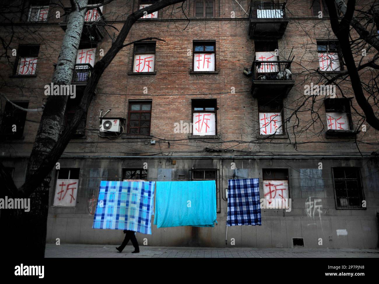 A man walks past an old apartment building set to be torn down, marked ...