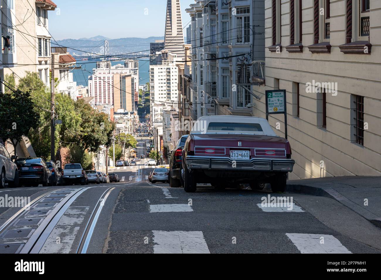 A sloped street in San Francisco, full of cars, seascape and tall ...