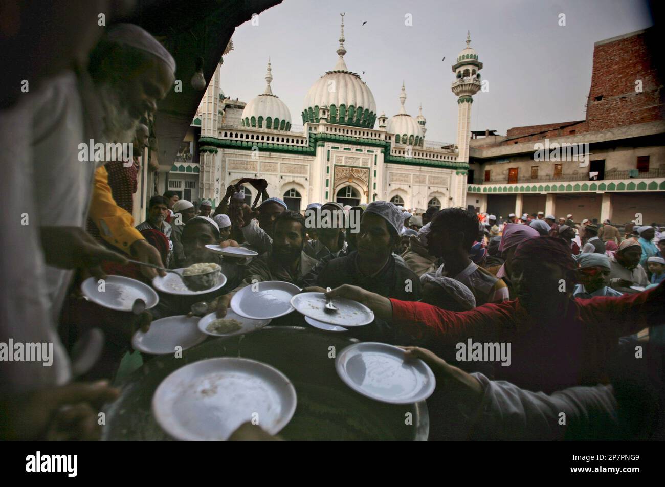 A cook at the mosque, left, distributes a traditional sweet dish among ...