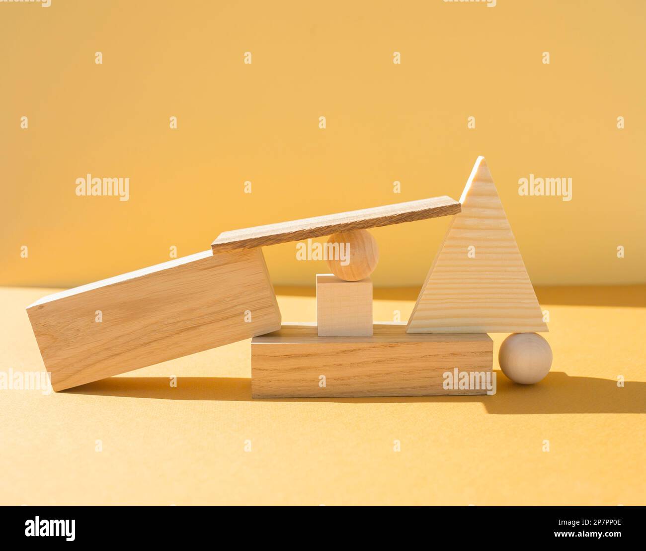 Three-dimensional wooden objects on yellow background. Balance and ...
