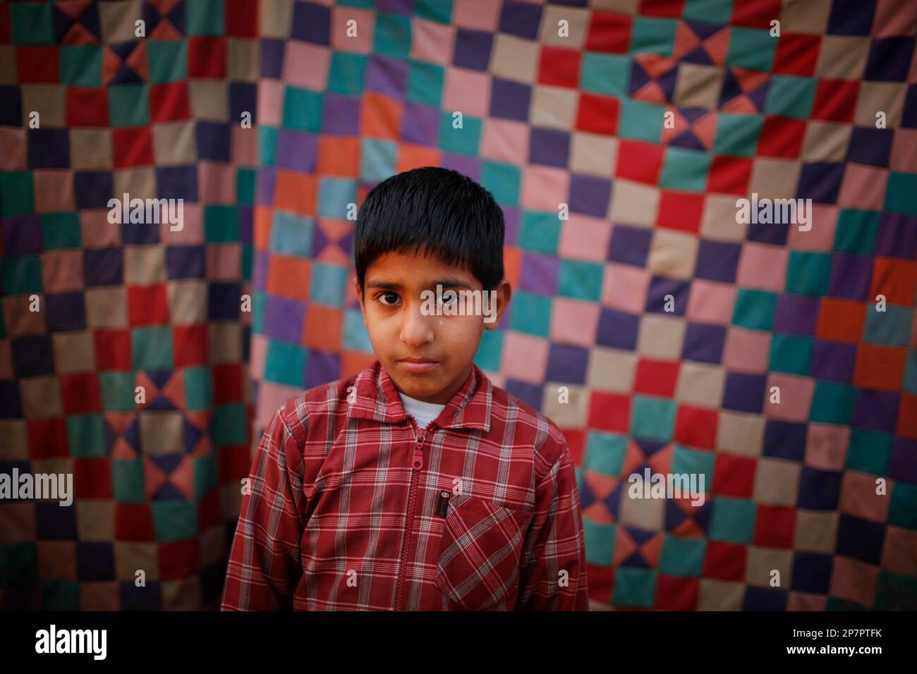 Aslam Chakasmi, 7, poses for a photo in front of his home in a poor ...