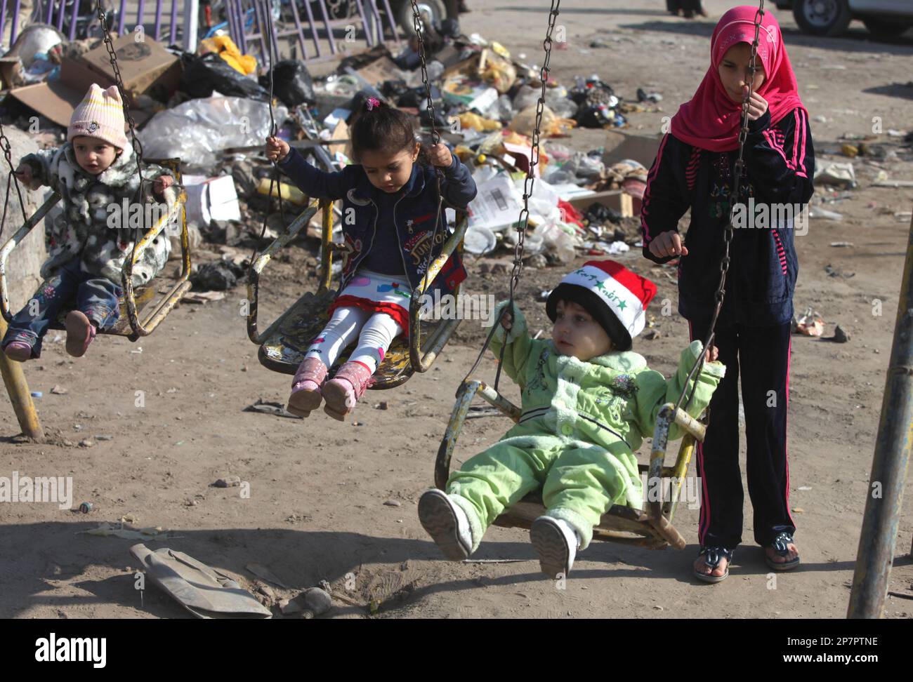 Iraqi children play on swings on the first day of Eid al-Adha in ...