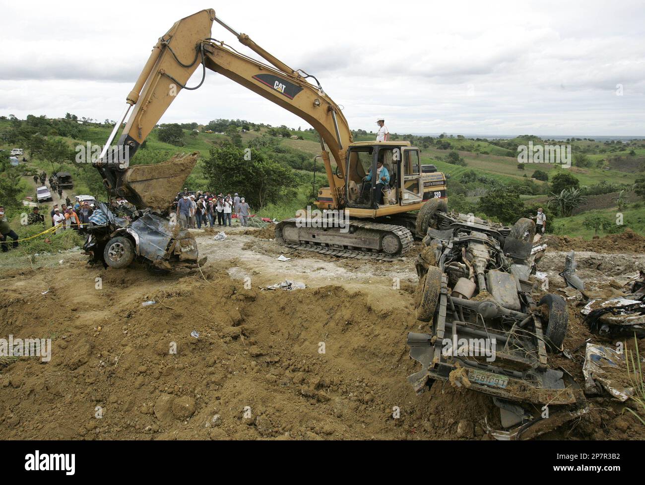 A backhoe pulls the wreckage of one of three vehicles that was dumped ...