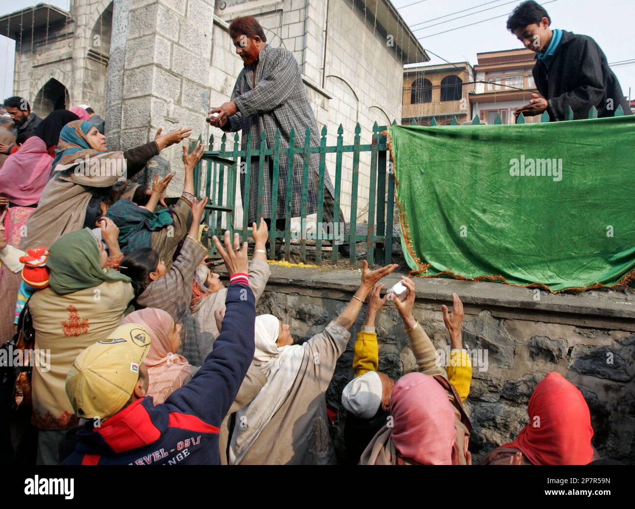 A Kashmiri man distributes sweets to the devotees outside the Shah-e ...