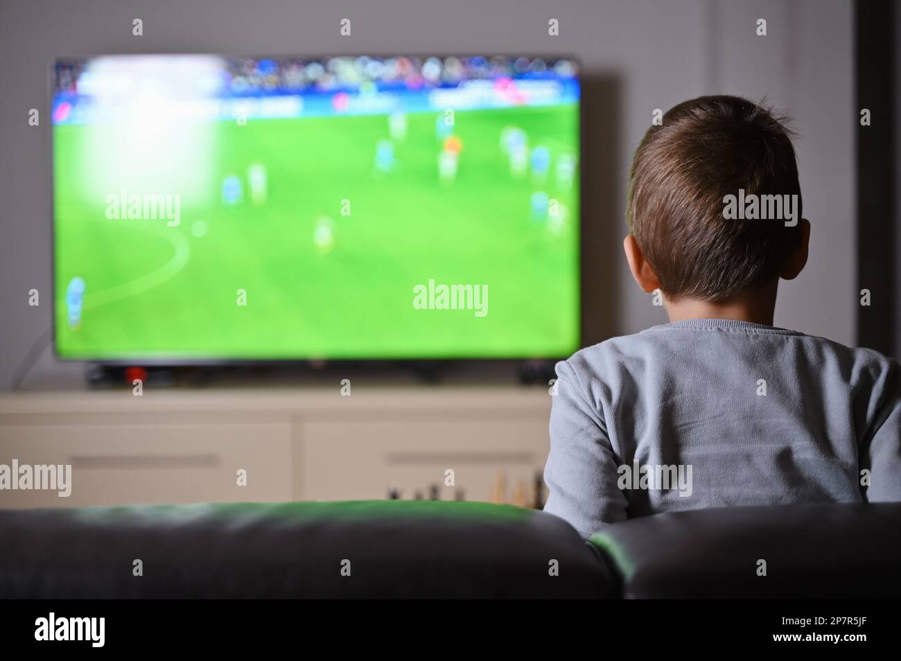 Boy sitting on sofa watching football on tv at Home Stock Photo - Alamy