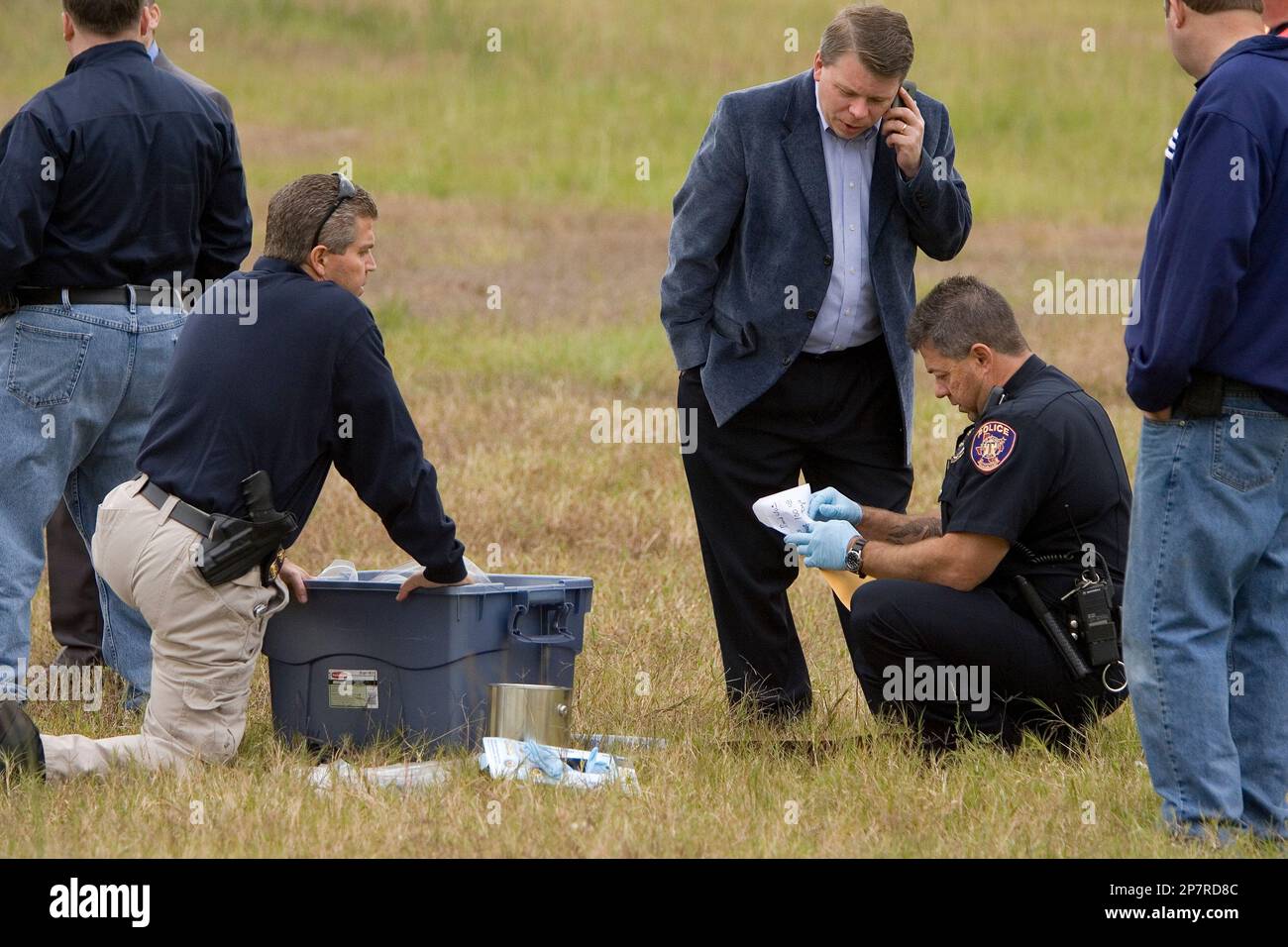 Federal agents and local authorities examine the contents of a suitcase ...