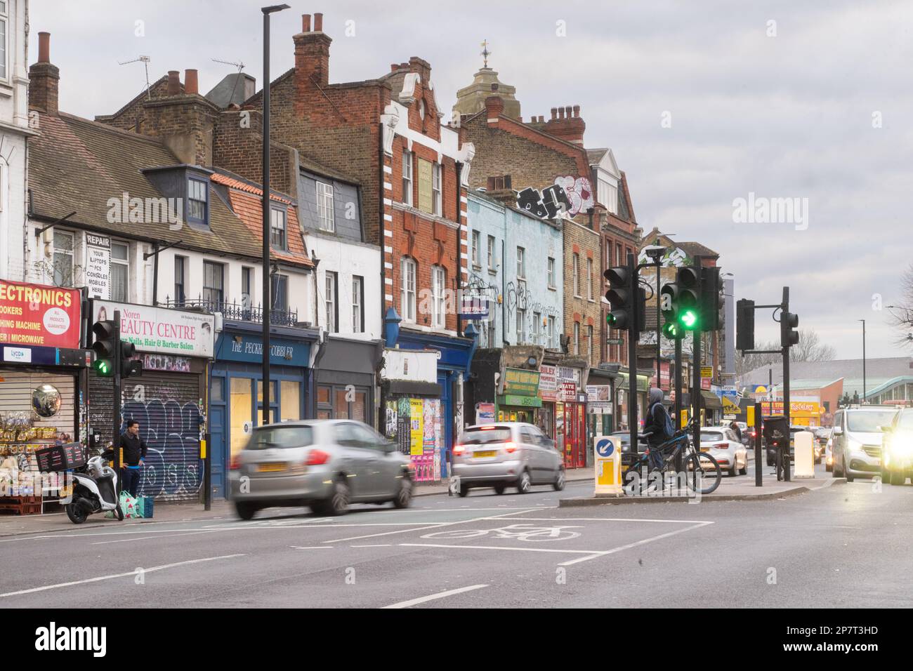 Pedestrians and vehicles cross a street in Peckham, London, SE15 ...