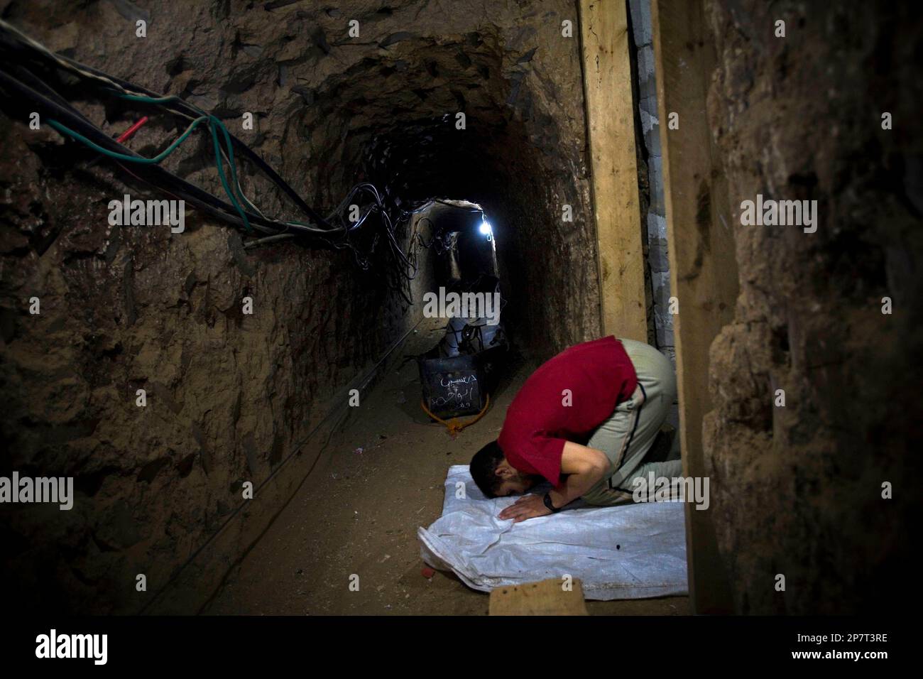 A Palestinian smuggler prays inside a tunnel running between Egypt and ...