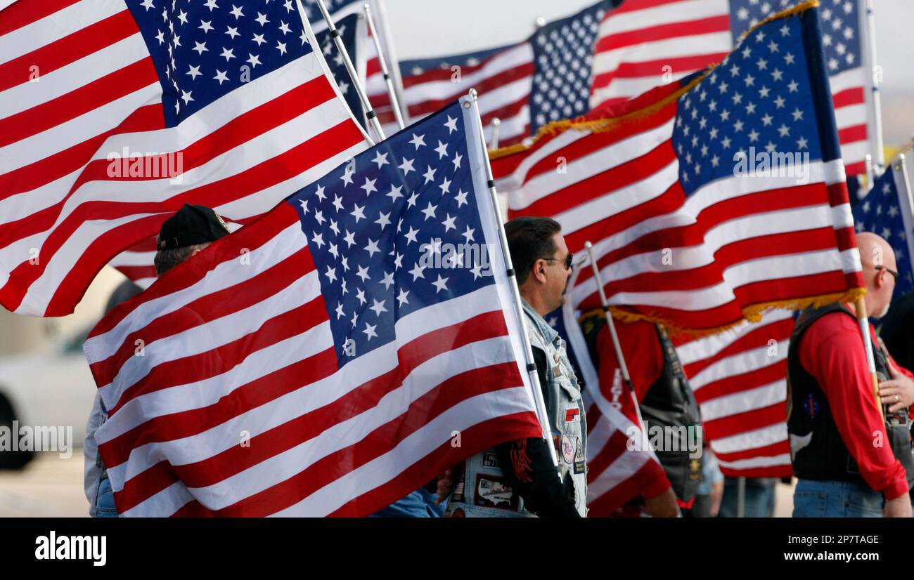 The Patriot Guard Riders carry U.S. flags to formation as they wait for ...