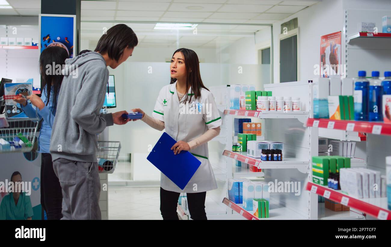 Female specialist taking notes about medicaments and helping clients ...