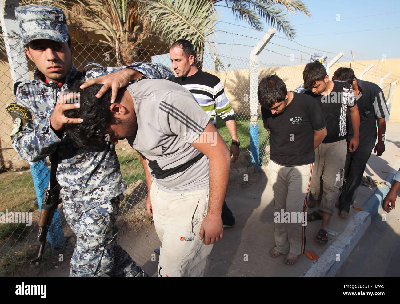 An Iraqi police officer leads four detainees in southwestern Baghdad ...