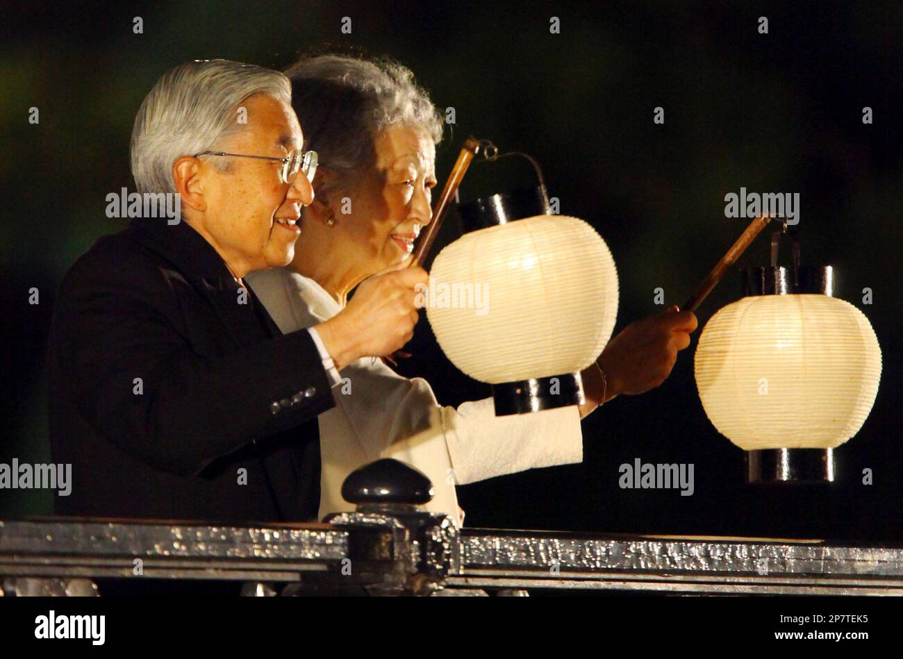 Japanese Emperor Akihito, left, and Empress Michiko wave paper lanterns ...
