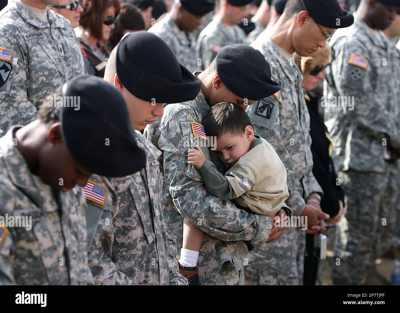An unidentified solider, third from left, holds his son as the prayer ...
