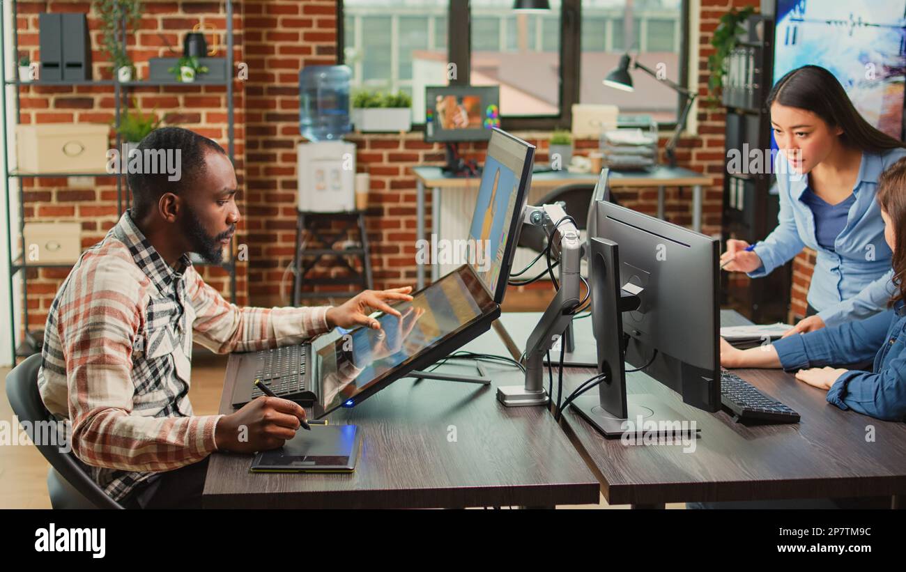 Graphic designer working on photo retouching with editing software, using tablet and stylus to ...