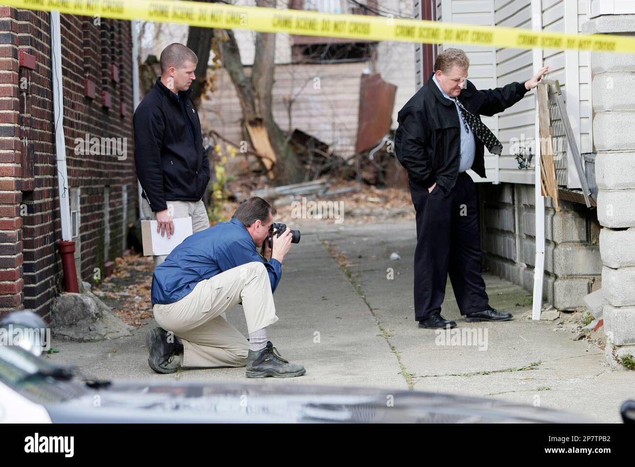 An FBI agent takes a photos of the underside of the front porch of the ...