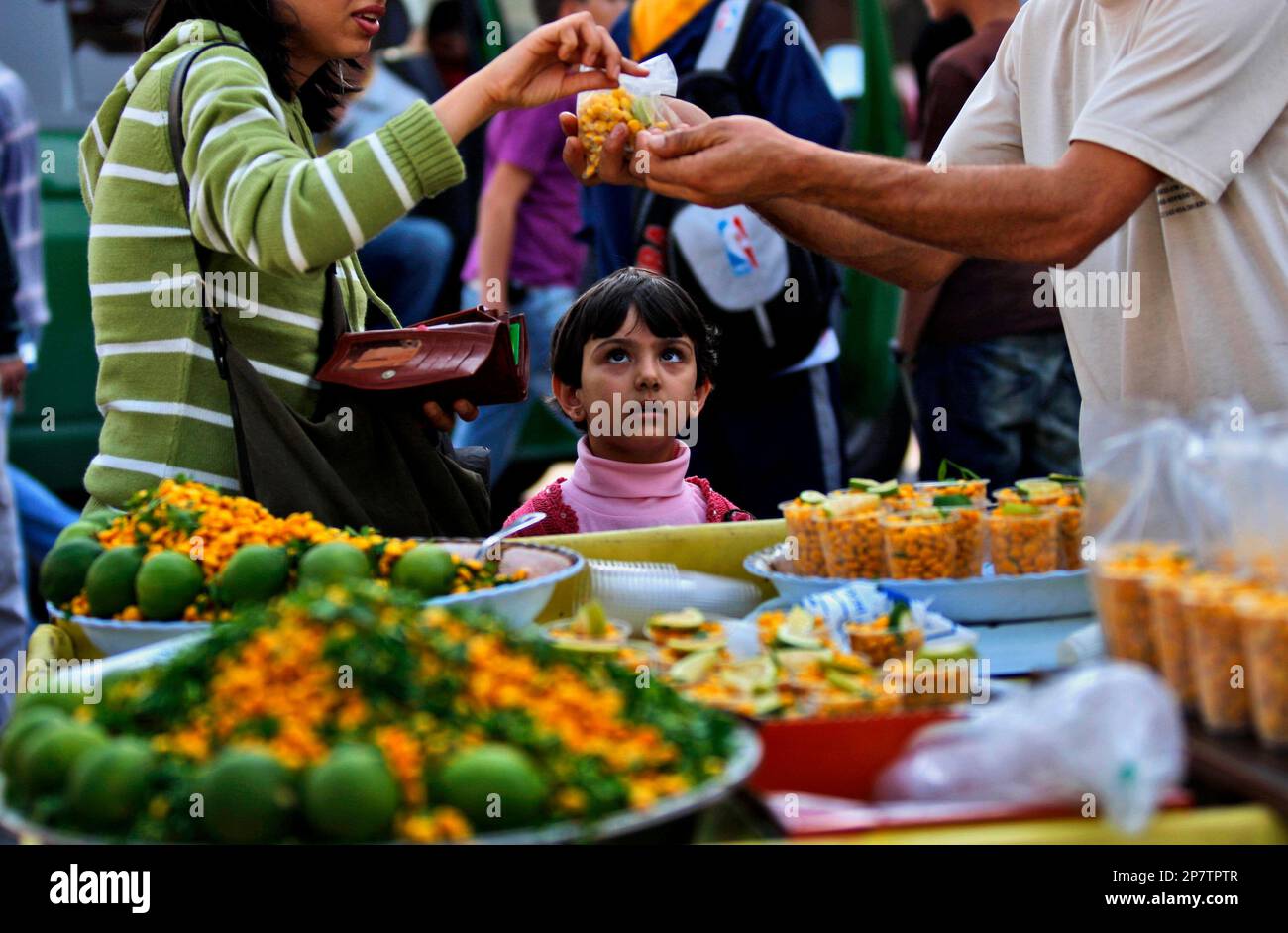 A Palestinian girl looks at a woman buying Lupini beans, called "Turmus ...