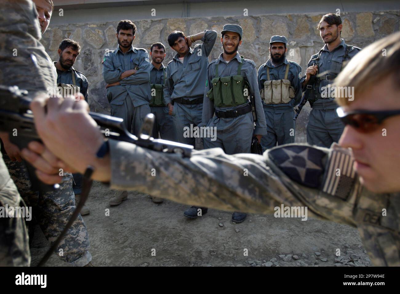 Afghan National policemen look on as U.S. soldier Cpl. Joseph Dement ...