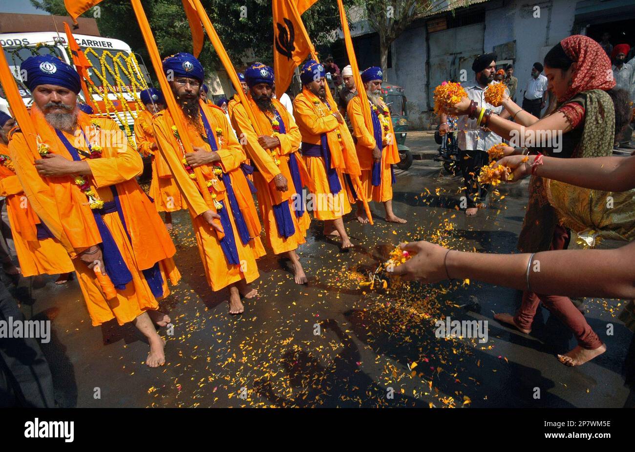 Sikh devotees throw flower petals on the road during a religious ...