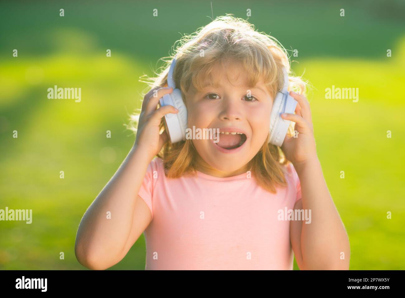 Screaming excited kid in headphones listening to music in backyard ...