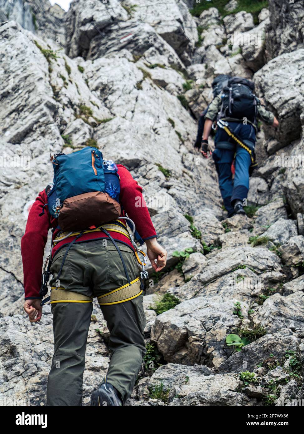 Two mountain climbers with backpack on a via ferrata route on a ...