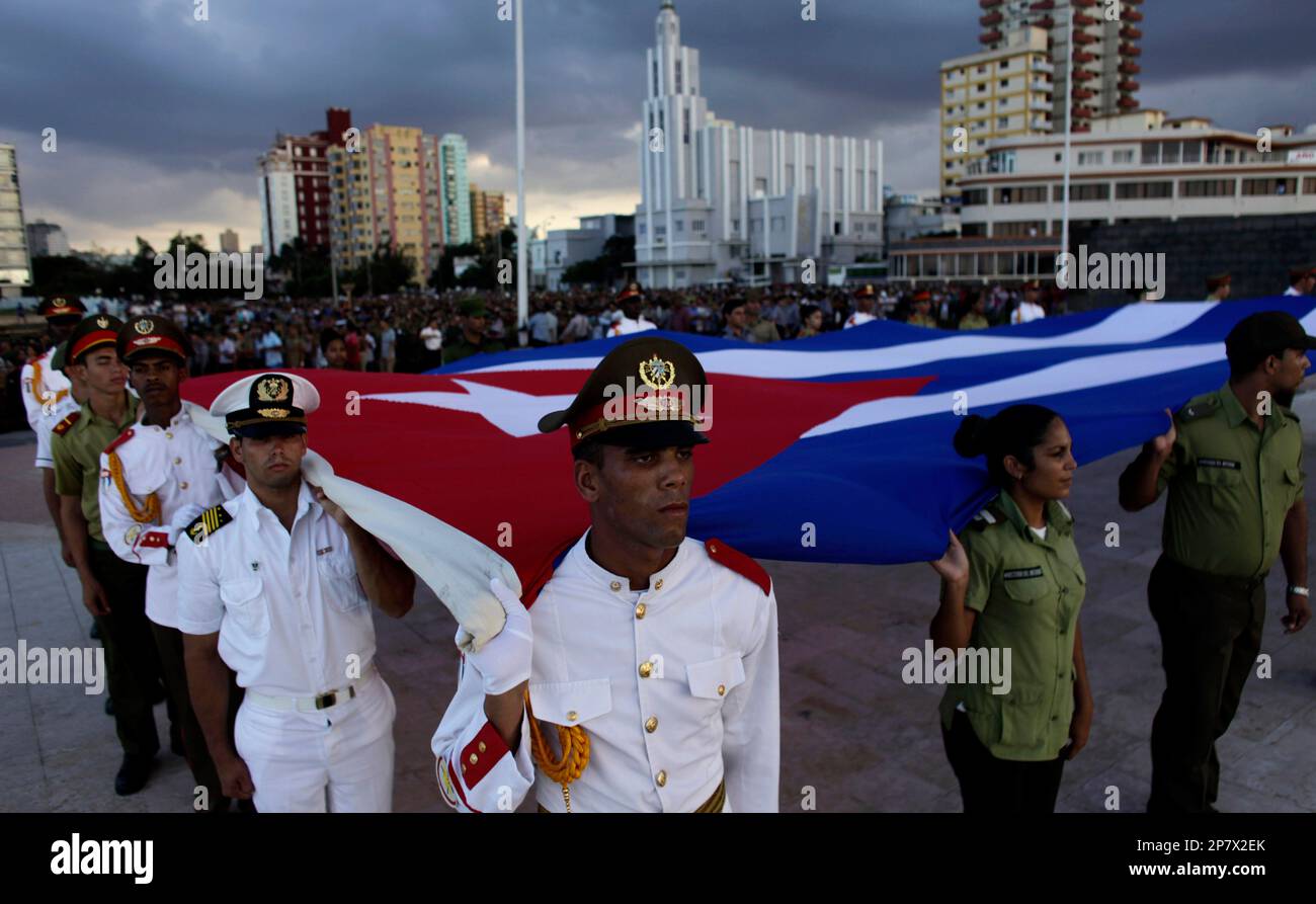 Cuban army and navy soldiers hold up a Cuban flag during a ceremony ...