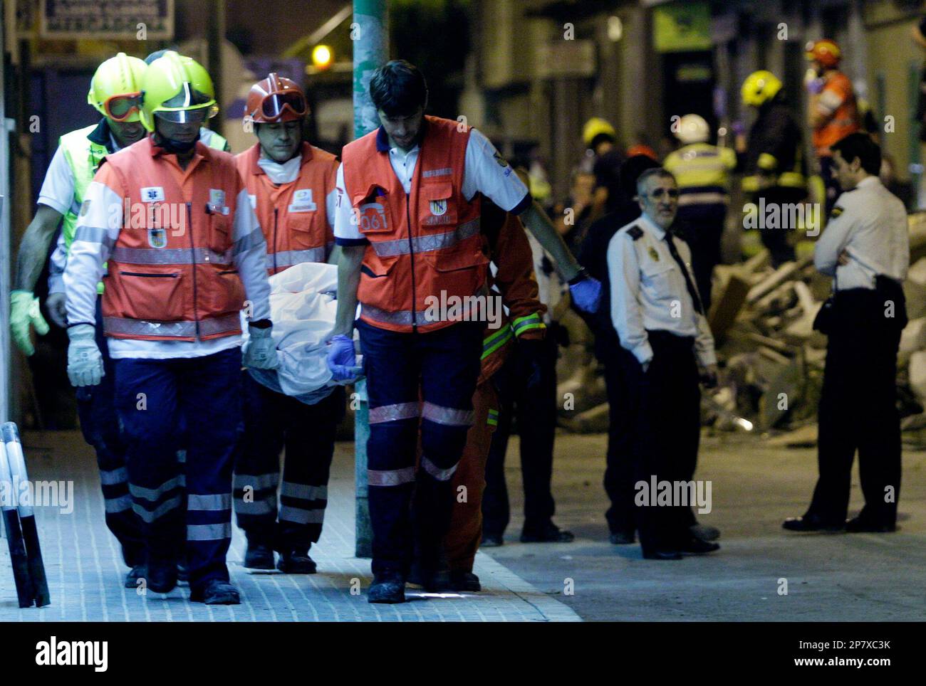 Rescuers carry the body of a person from a small apartment building ...